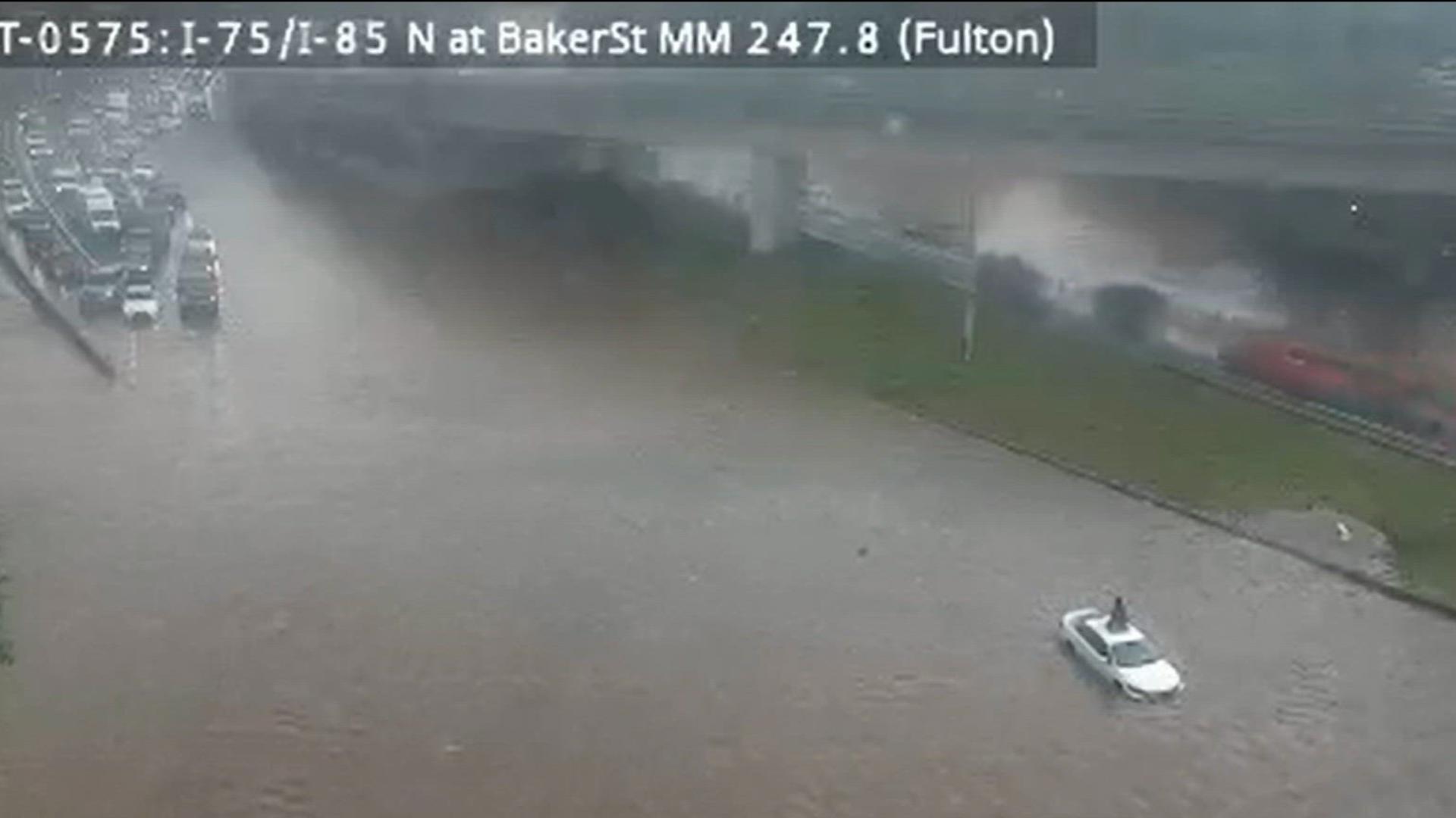 Driver climbs onto roof of car after getting trapped in massive flood ...
